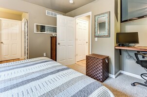 A bedroom with a bed, a desk with a computer, a mirror, and a wardrobe.