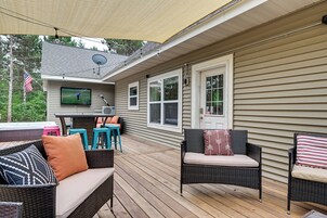 A covered deck with outdoor furniture, a television, and a satellite dish.