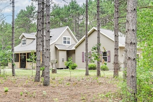 A two-story house with a gabled roof, surrounded by tall pine trees.