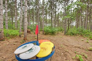 Uma cesta de metal azul com frisbees numa trilha na floresta.
