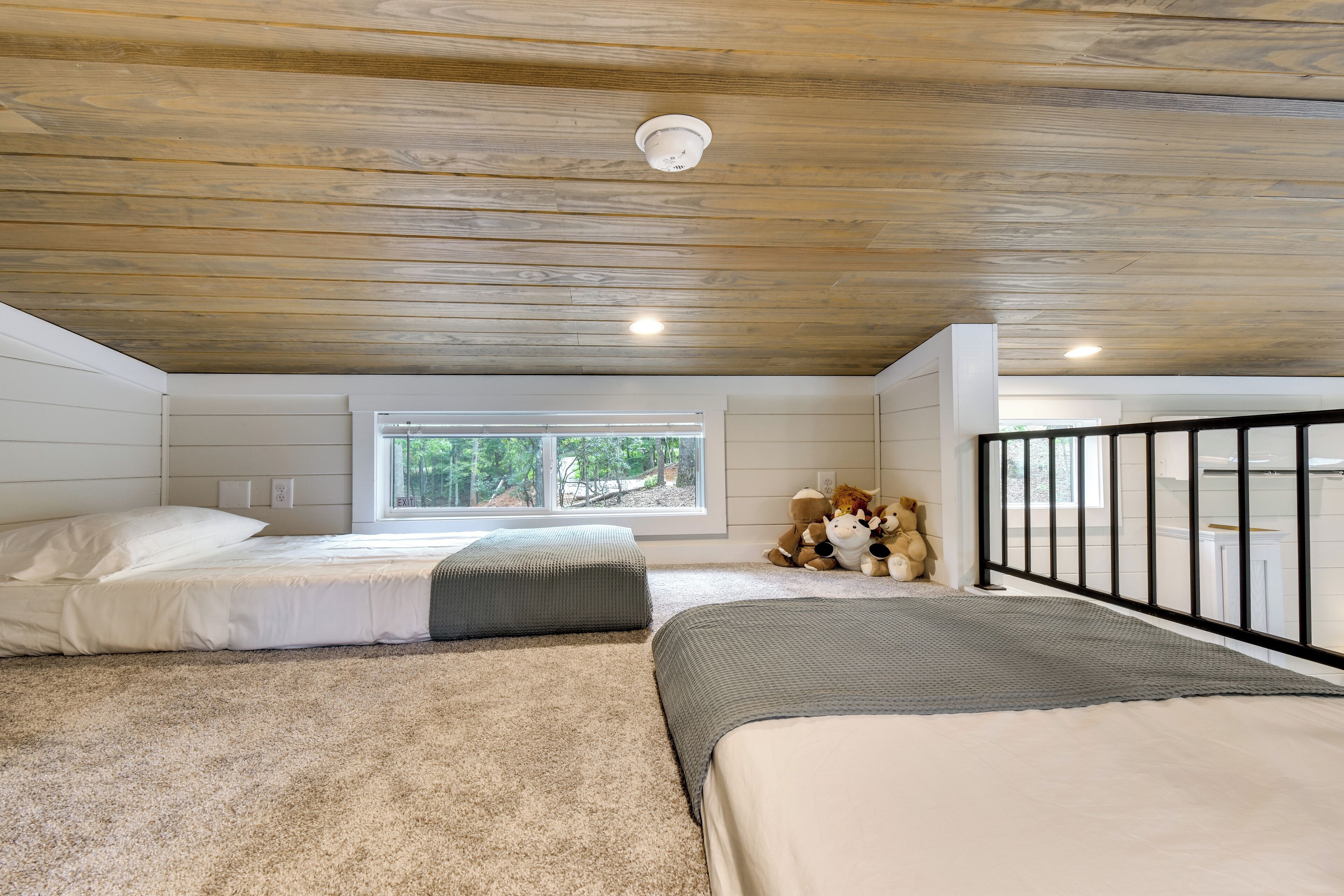 Quarto com duas camas, uma janela e vista para árvores.