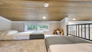 Quarto com duas camas, uma janela e vista para árvores.