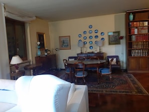 Uma sala de jantar com uma mesa redonda, cadeiras e uma parede decorada com pratos azuis.