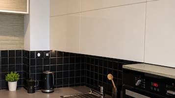 Uma cozinha moderna com uma pia de aço inoxidável, painel de azulejos preto e branco, uma cafeteira e um forno embutido.