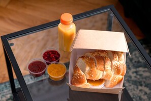 Mesa de vidro com uma caixa de pães e uma garrafa de suco de laranja.