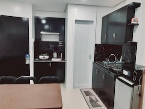 Uma cozinha compacta com mesa de jantar, cadeiras e geladeira.