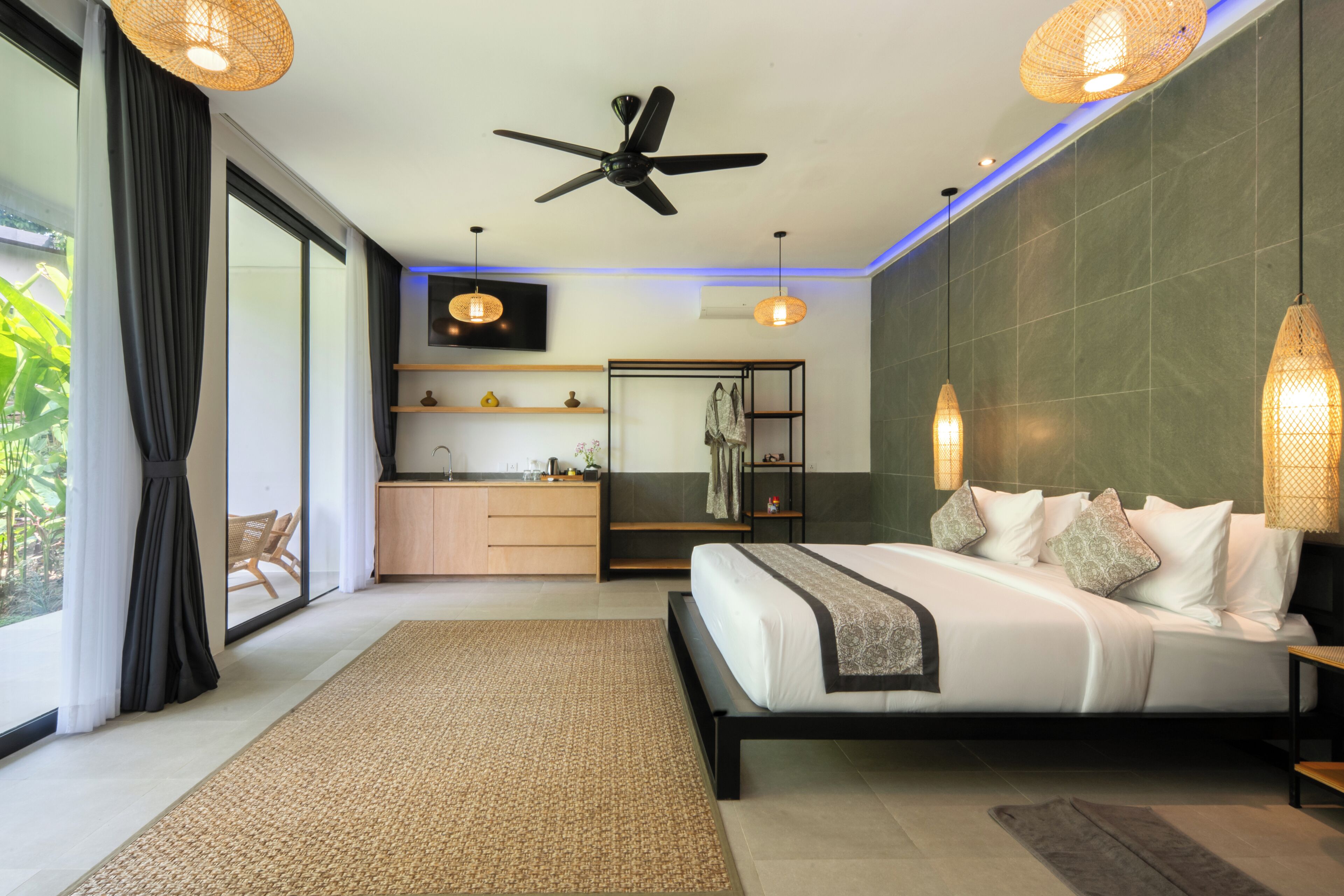 Quarto moderno com cama grande, ventoinha no teto e televisão na parede.