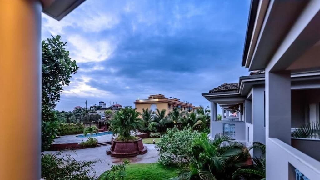 Um bairro residencial com piscina, palmeiras e um prédio com telhado plano.