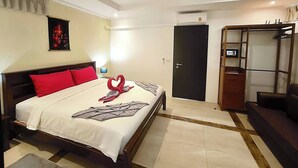 Quarto de hotel com cama, guarda-roupa, escrivaninha e espelho.