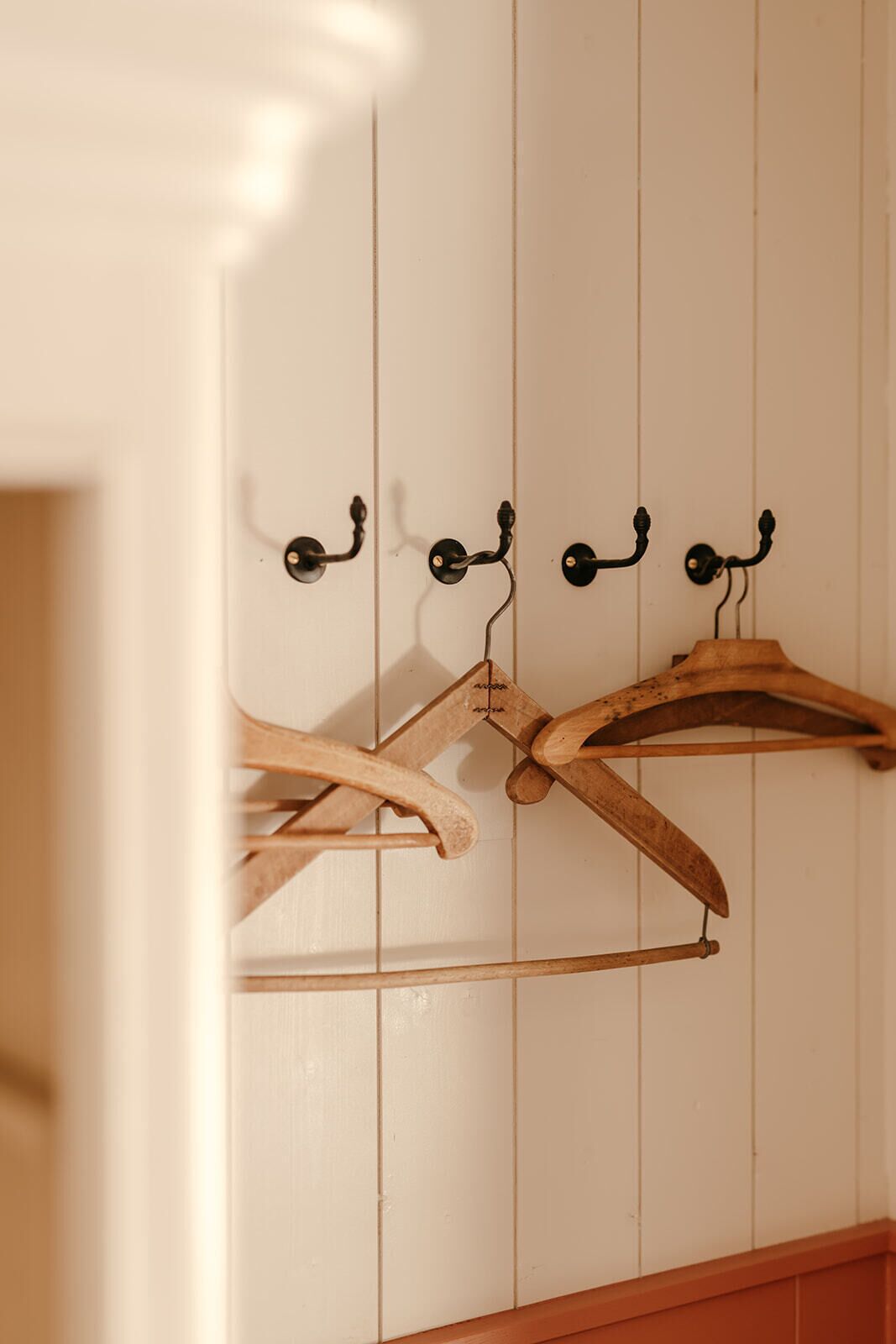 Um guarda-roupa de madeira com vários cabides e um porta-casacos.