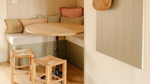 Quarto aconchegante com um banco embutido, banquetas de madeira, um cesto pendurado e um cabideiro.