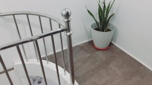 Uma escadaria com guarda-corpo de metal e um vaso de planta ao lado.
