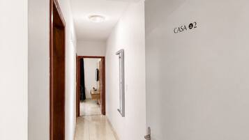 Um corredor com uma porta identificada como 'CASA 2' que dá para um quarto.
