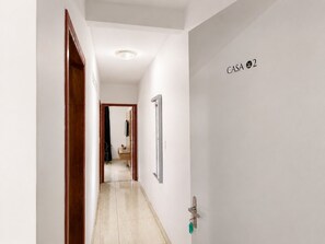 Um corredor com uma porta identificada como 'CASA 2' que dá para um quarto.