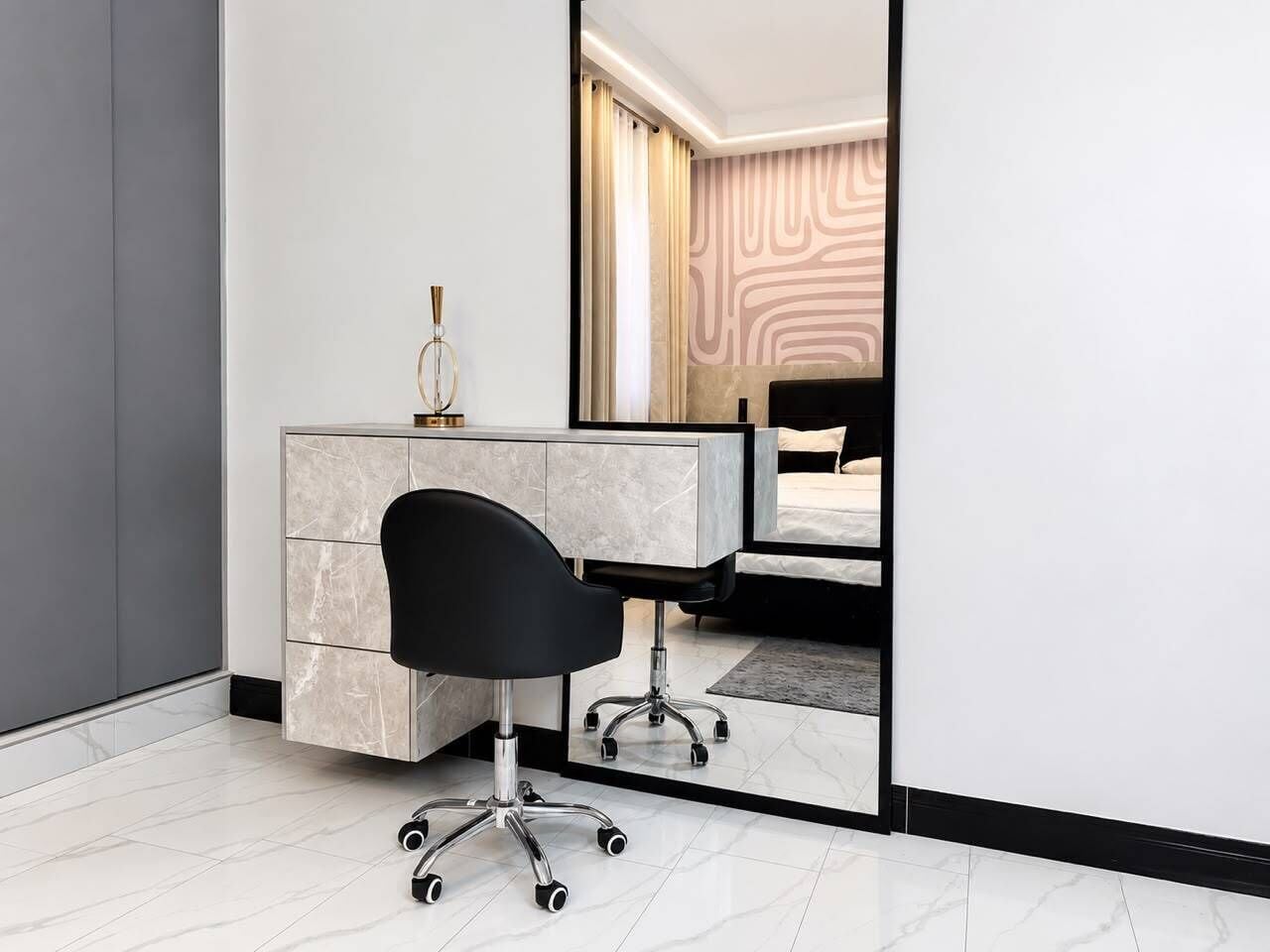 A modern bedroom with a large bed, a bedside table, and a mirror reflecting the room.