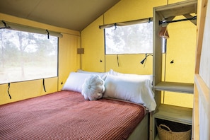 A single bed with a red and white patterned bedspread, two white pillows, and a wooden headboard.