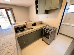 Uma cozinha com bancada de granito, eletrodomésticos de aço inoxidável e armários verdes.