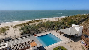 Um imóvel à beira-mar com piscina, acesso direto à praia e vista para o oceano.