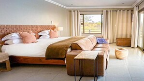 Quarto moderno com uma cama grande, um sofá, uma mesinha e vista para o exterior.