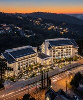 Um hotel grande, com vários andares, apresenta um design arquitetônico moderno, uma entrada imponente e fachada bem iluminada.