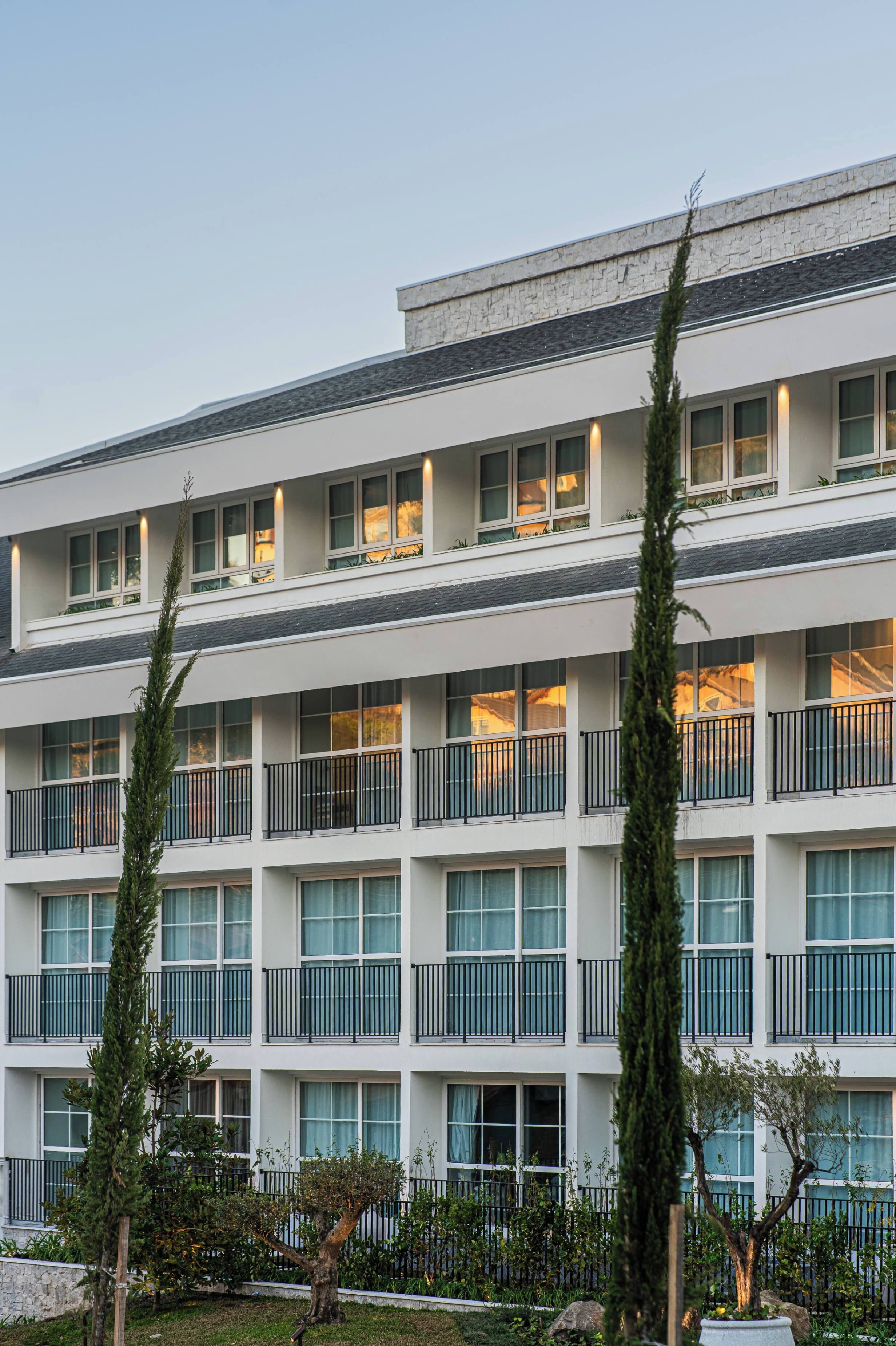 Um hotel com vários andares, varandas e grandes janelas.