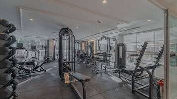 Academia com diversos equipamentos de ginástica, amplas janelas e design moderno e impecável.