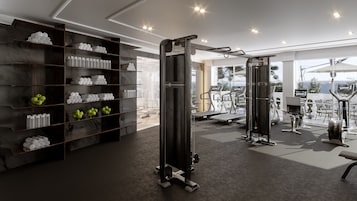 Uma academia com equipamentos de exercícios, uma parede de mármore e prateleiras com toalhas e garrafas.