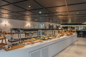 Disposição de buffet com diversos alimentos e uma estação de grelhados.