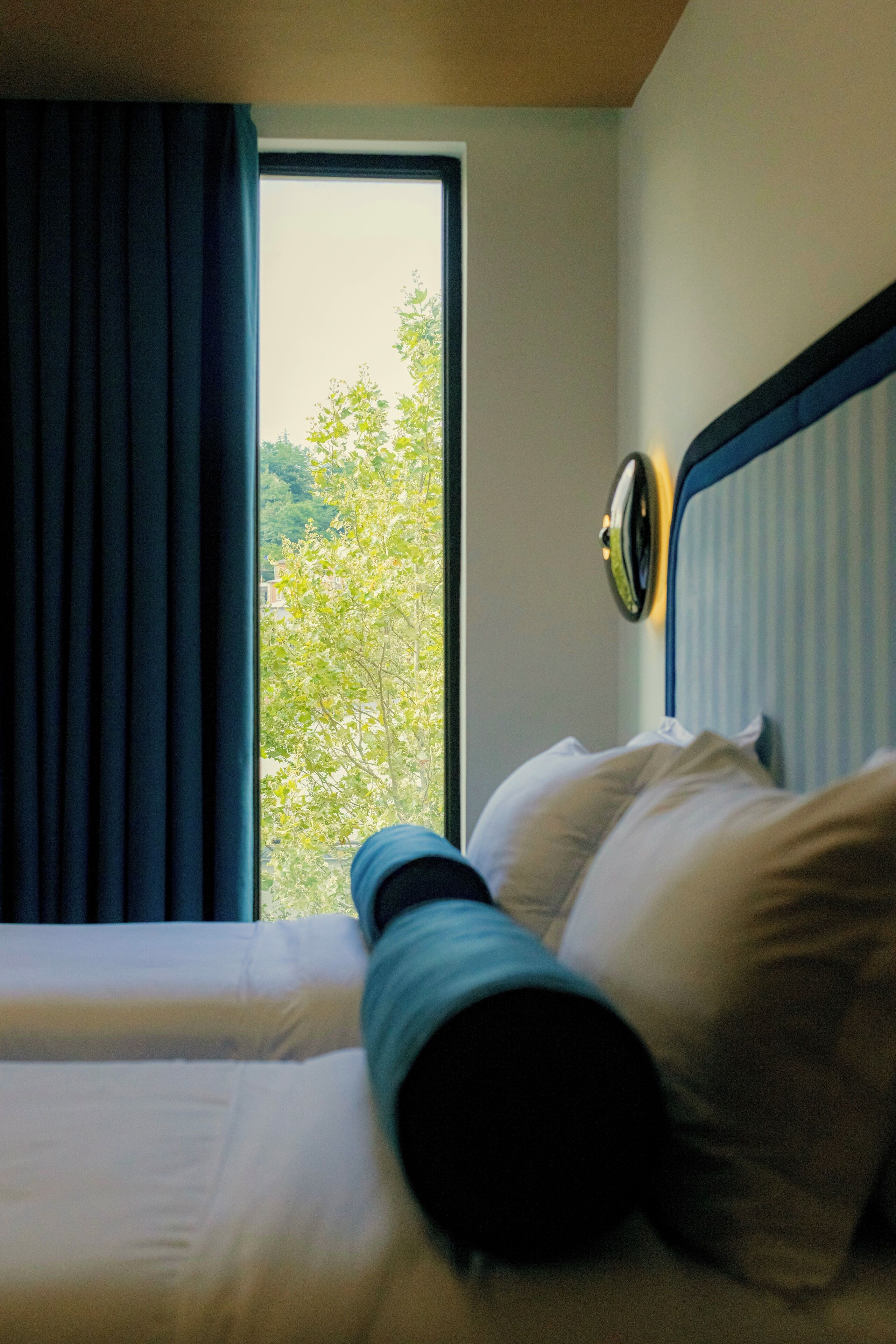 Quarto de hotel com uma cama, uma janela e vista para árvores.