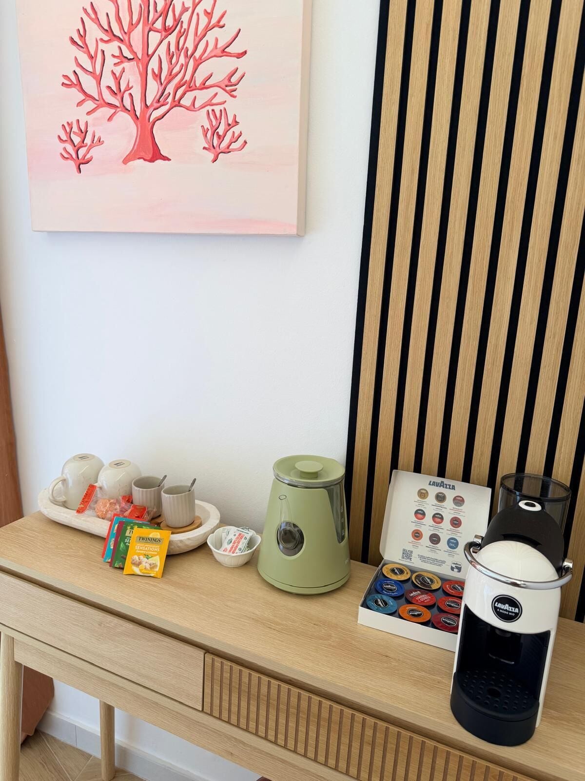 Uma mesa de madeira com chaleira, bule, xícaras e máquina de café.