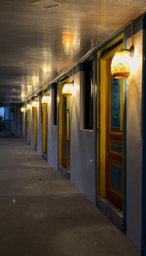 Um corredor com portas, cada uma com uma luminária acima.