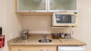 Uma cozinha equipada com micro-ondas, pia e armários.