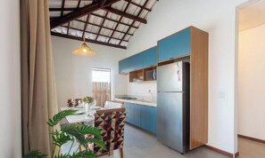 Uma cozinha moderna com armários azuis, uma geladeira de aço inoxidável e um espaço de refeições com mesa posta para dois.