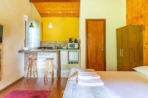 Quarto compacto com cozinha compacta, cama e guarda-roupa.
