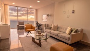 Uma sala de estar moderna com uma mesa de centro de vidro, um sofá e uma poltrona.