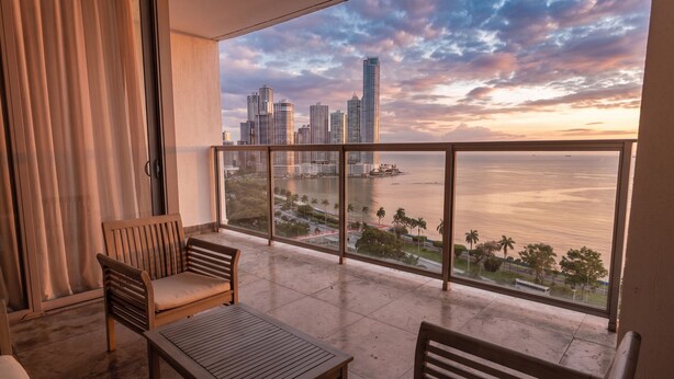 Uma varanda com vista para o horizonte urbano e um corpo de água.