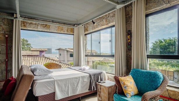 Quarto com cama, uma cadeira e vista para o exterior.