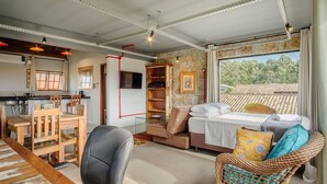 Um quarto aconchegante com uma cama, área de refeições e cozinha.