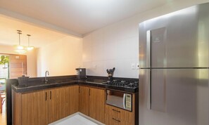 Uma cozinha moderna com armários de madeira, uma geladeira de aço inoxidável, forno embutido e fogão a gás.