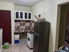 Uma cozinha compacta com geladeira, fogão e armários.