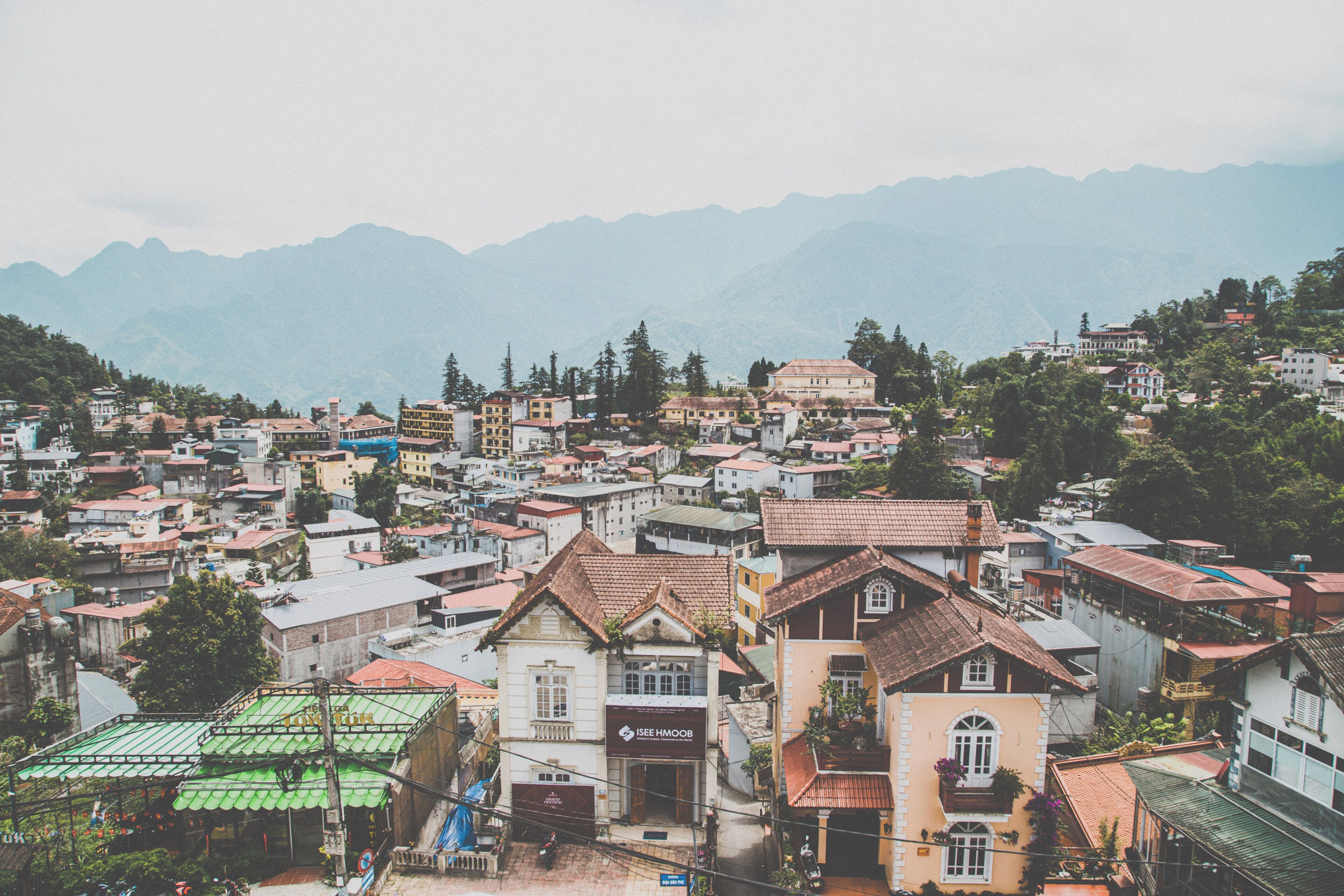 Uma área urbana densamente povoada com diversos tipos de construções, incluindo edifícios residenciais e comerciais, ao fundo uma paisagem montanhosa.