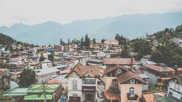 Uma área urbana densamente povoada com diversos tipos de construções, incluindo edifícios residenciais e comerciais, ao fundo uma paisagem montanhosa.