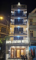 Um edifício com vários andares e uma placa com a inscrição 'SAPA STATION HOTEL'.