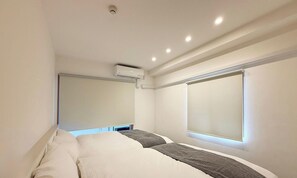 Quarto moderno com cama, janela e unidade de ar condicionado no teto.
