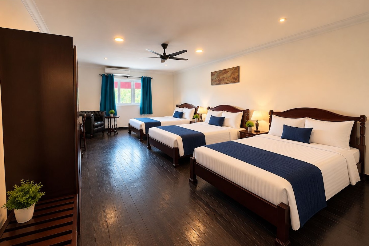 Quarto de hotel com duas camas, um ventilador de teto e janela com cortinas.