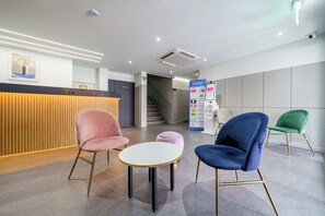 Área de recepção com balcão, escada e assentos com mesa pequena.