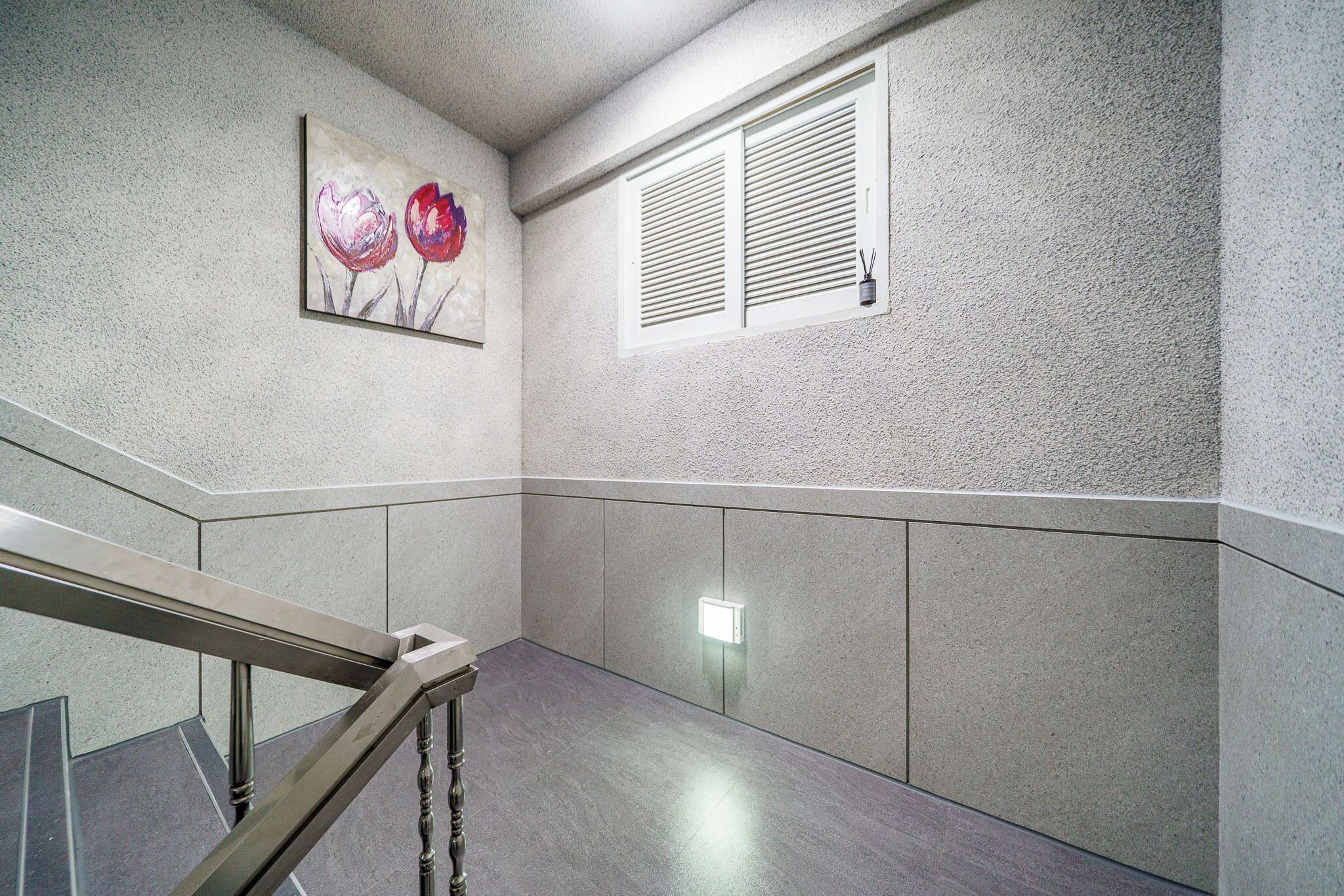 Interior moderno com escada, um respiradouro fixado na parede e um quadro.