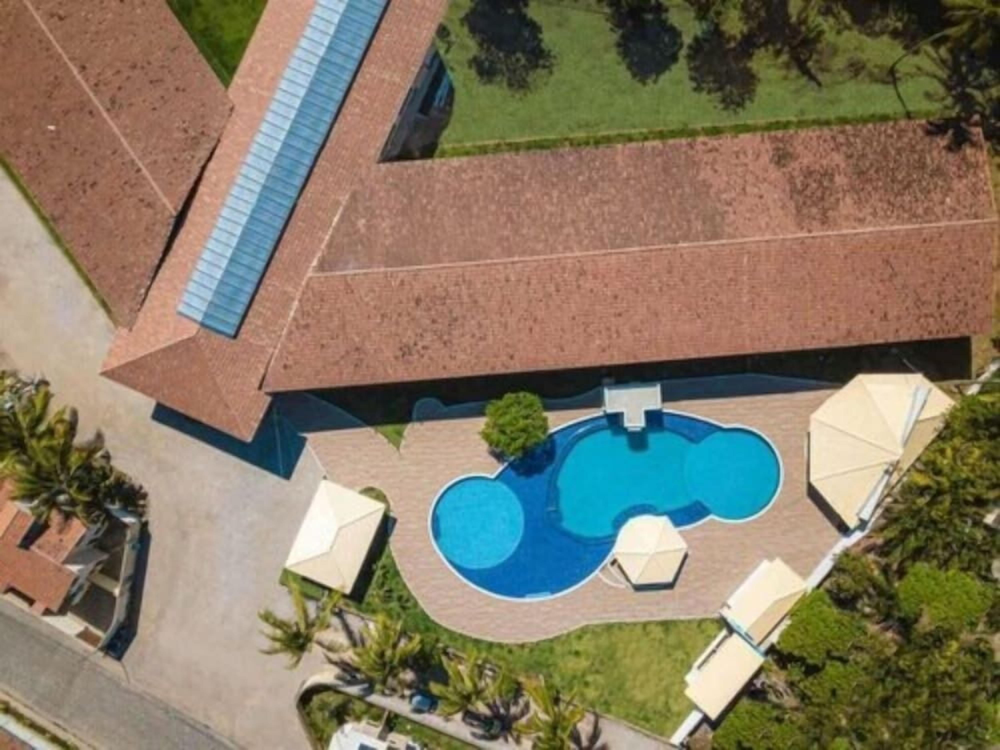 Vista aérea de um hotel com piscina, espreguiçadeiras e área ajardinada.