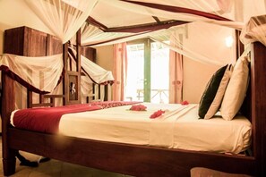 Uma cama com dossel, um guarda-roupa de madeira e uma porta que dá para uma área externa.