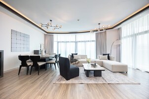 Uma sala de estar moderna com área de jantar, apresentando um sofá, cadeiras, uma mesa de centro e um lustre.